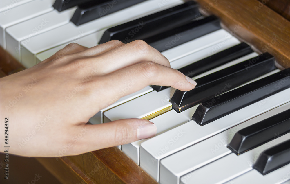 Girl's left hand holding pressed keys on a piano Stock Photo | Adobe Stock