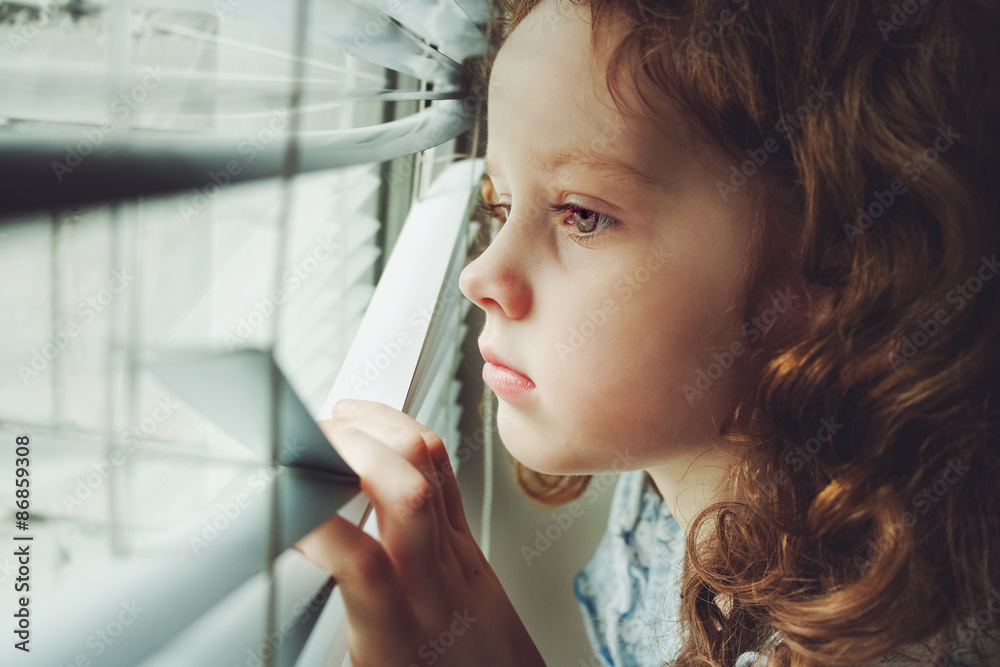 Little child looking out the window through the blinds. Backgrou Stock ...