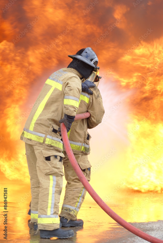 fire-fighter with hose fighting large wall of fire Stock Photo | Adobe ...