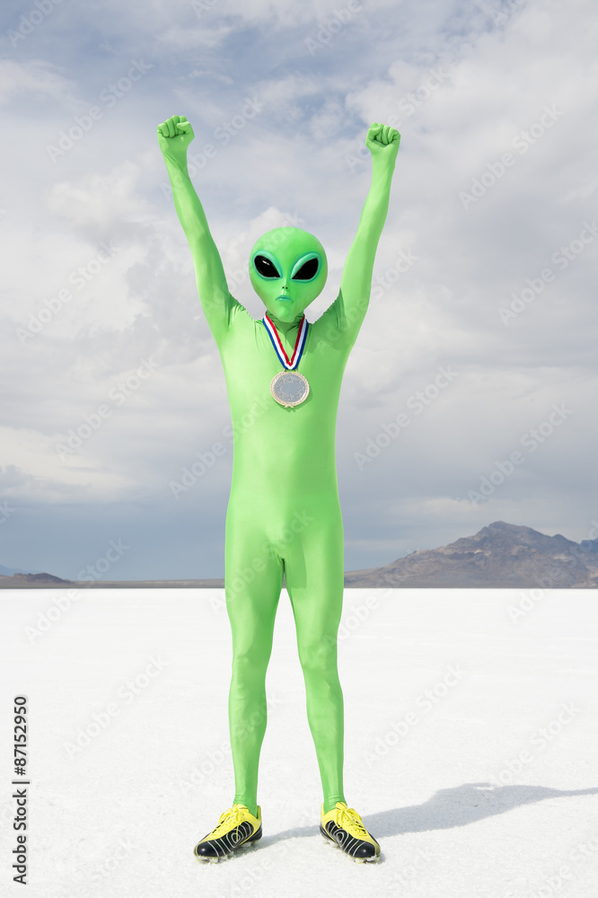 Green alien athlete wearing gold medal standing with arms raised on ...