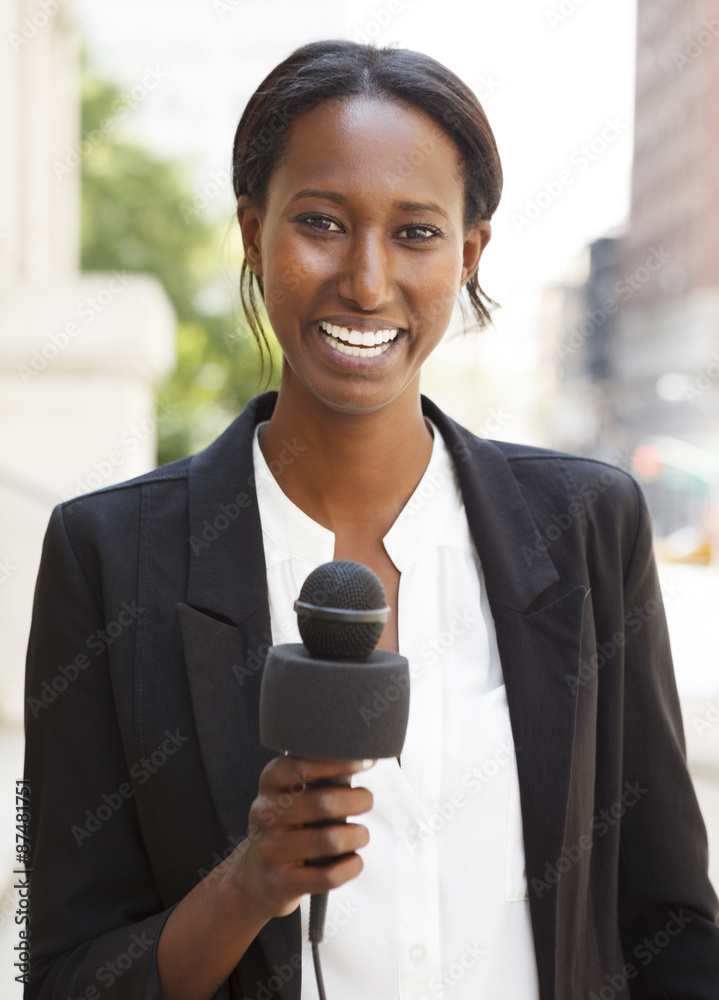 An cheerful female reporter on a city street. Stock Photo | Adobe Stock
