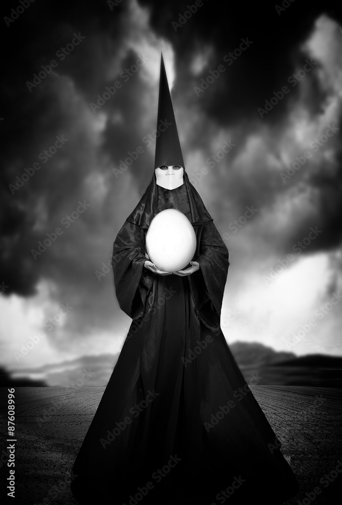 Strange person in black cloak with an egg Stock Photo | Adobe Stock