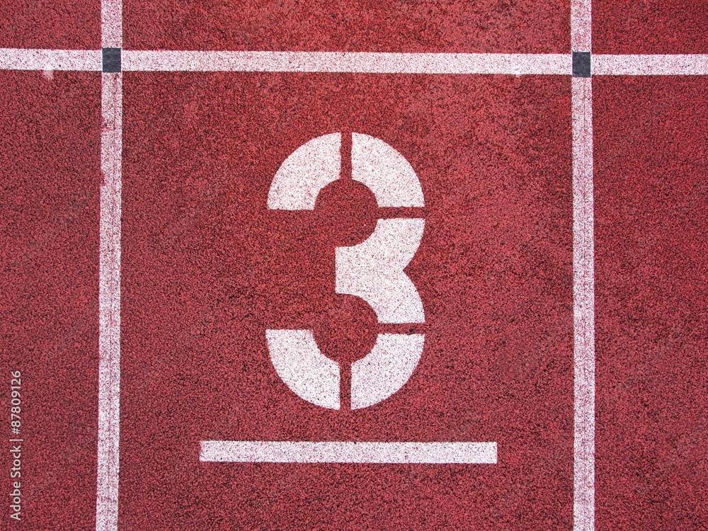 Number three. White track number on red rubber racetrack, texture of ...