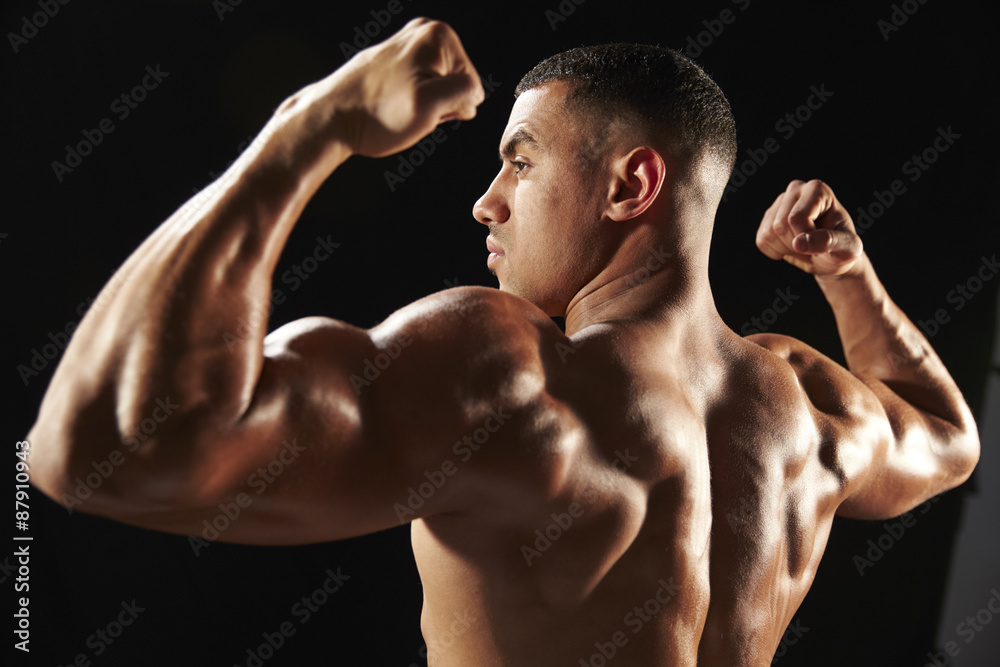 Male bodybuilder flexing muscles, side view Stock Photo | Adobe Stock
