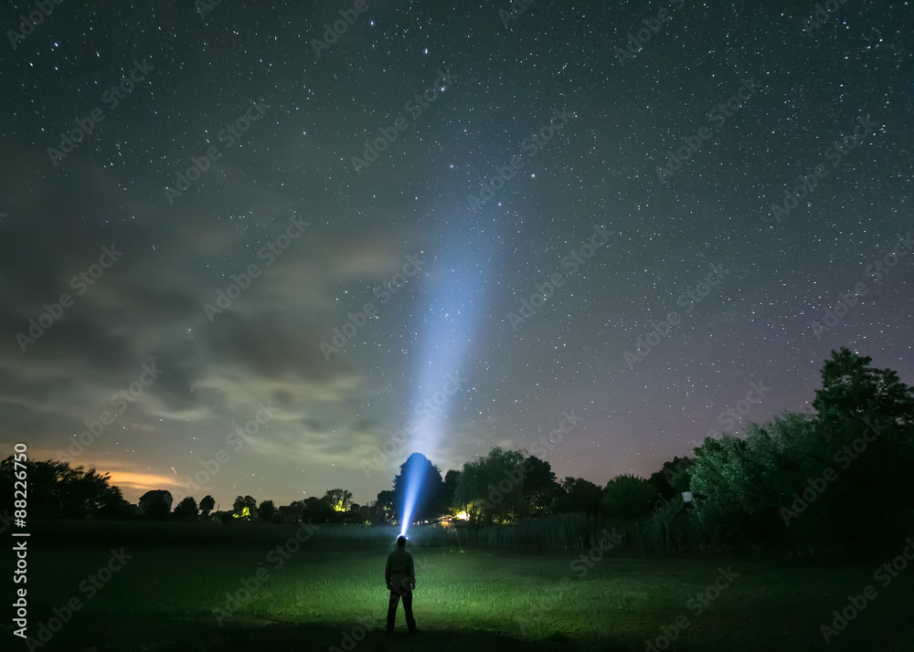 Man with headlight standing in the starry night. The beam of the light ...