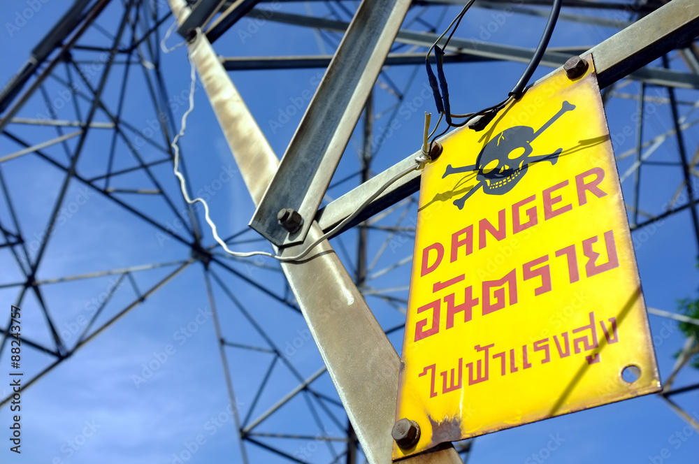 colorful danger warning sign hanging on steel framework of high voltage ...