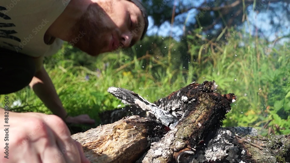 Man fanning the flames of a fire in nature. Video with sound. You can ...