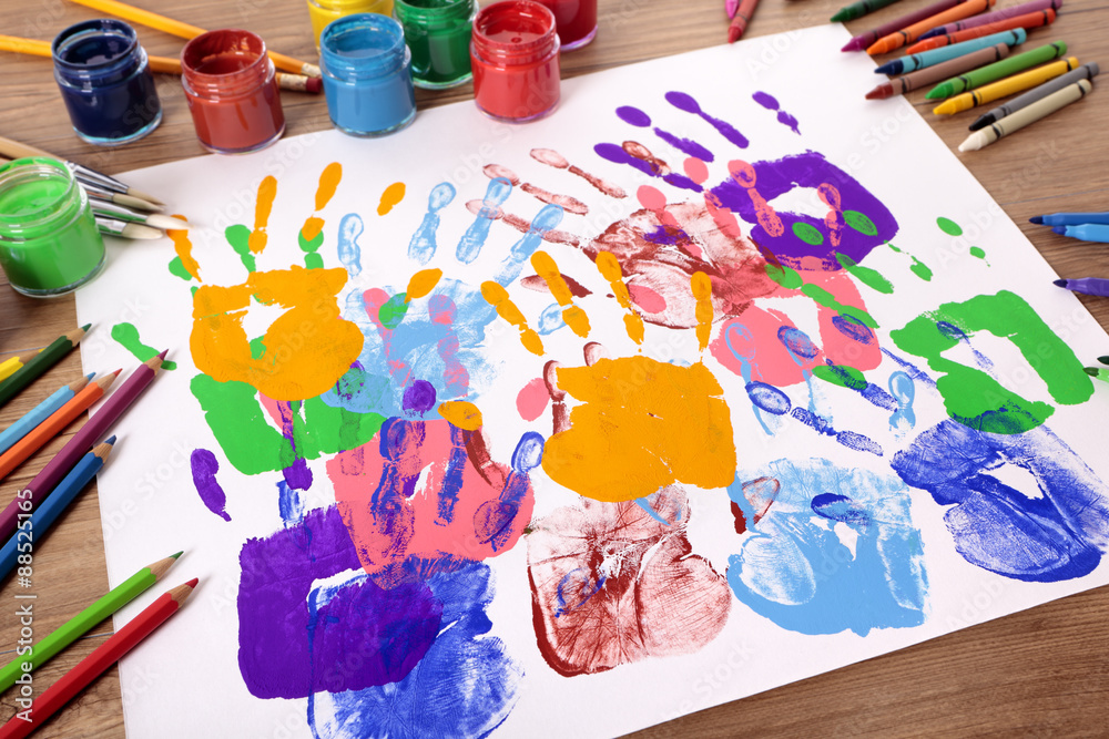 Child handprints or hand prints and art equipment on a school desk with ...