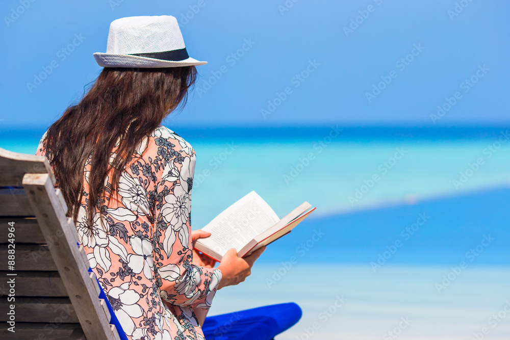 Beautiful woman reading on beach at lounger Stock Photo | Adobe Stock
