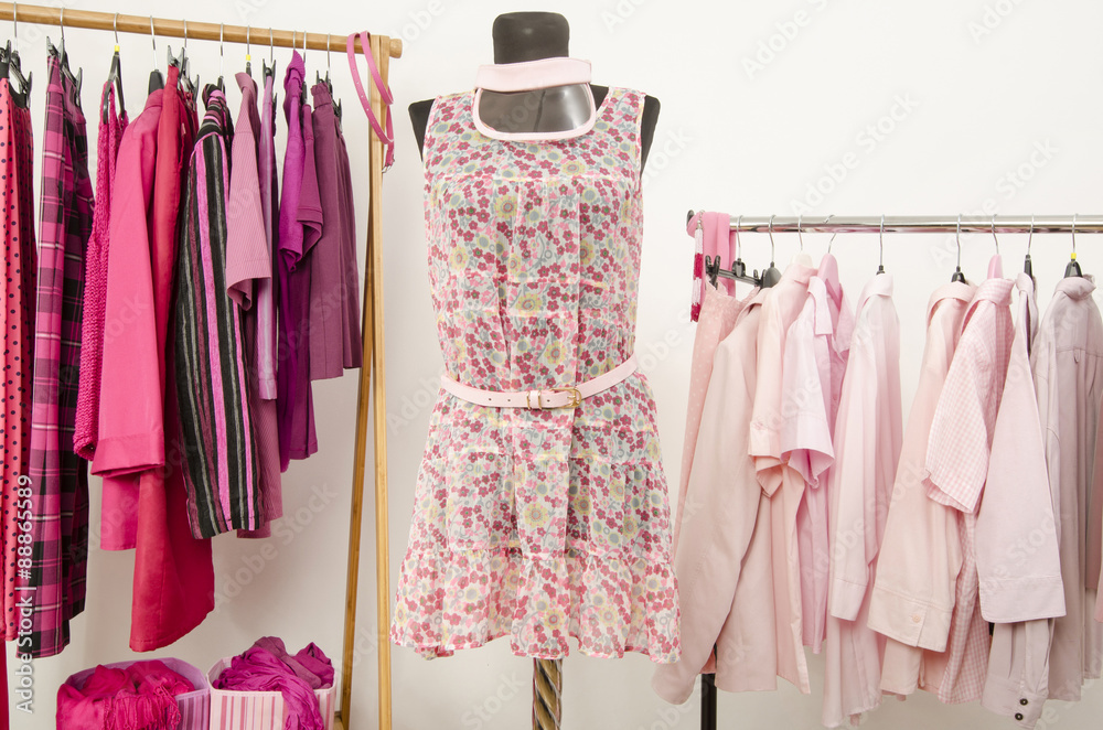 Dressing closet with pink clothes arranged on hangers and a summer ...