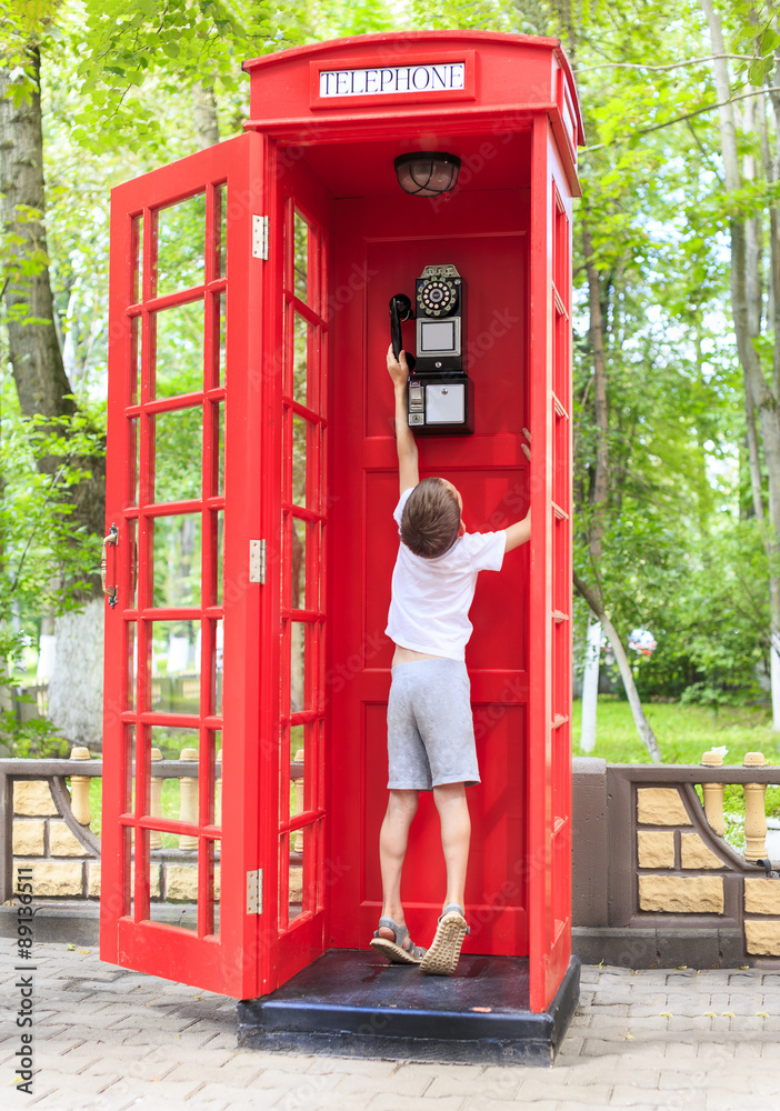 boy in a phone booth. the child reaches for the tube in a telephone box ...