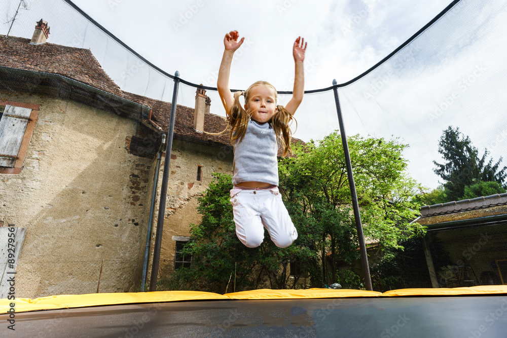 Cute preschooler girl jumping on trampoline Stock Photo | Adobe Stock