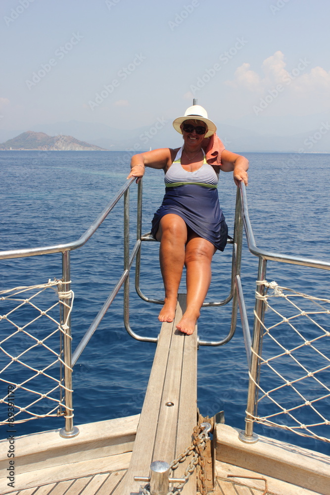 A mature woman wearing sunglasses and a hat while on a boat trip during ...