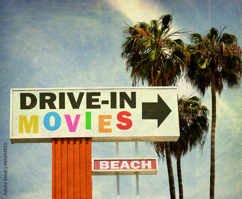 aged and worn vintage photo of retro drive in movies sign with palm ...