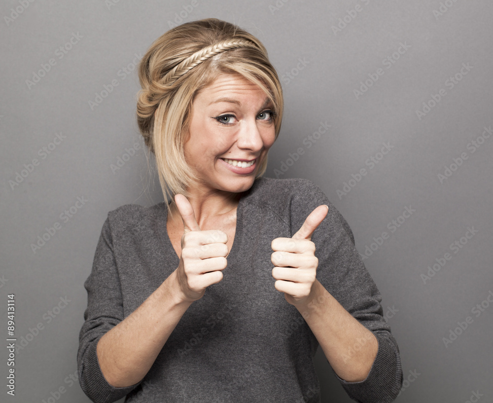 agreement concept - smiling young blonde woman giving a double thumb up ...