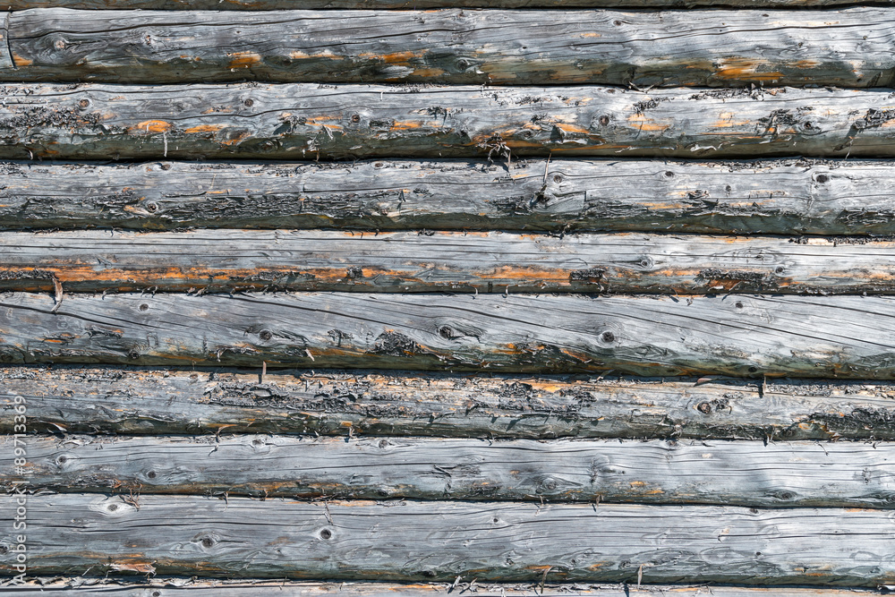 Weathered gray log house wood wall with a highlight from the sun on the ...