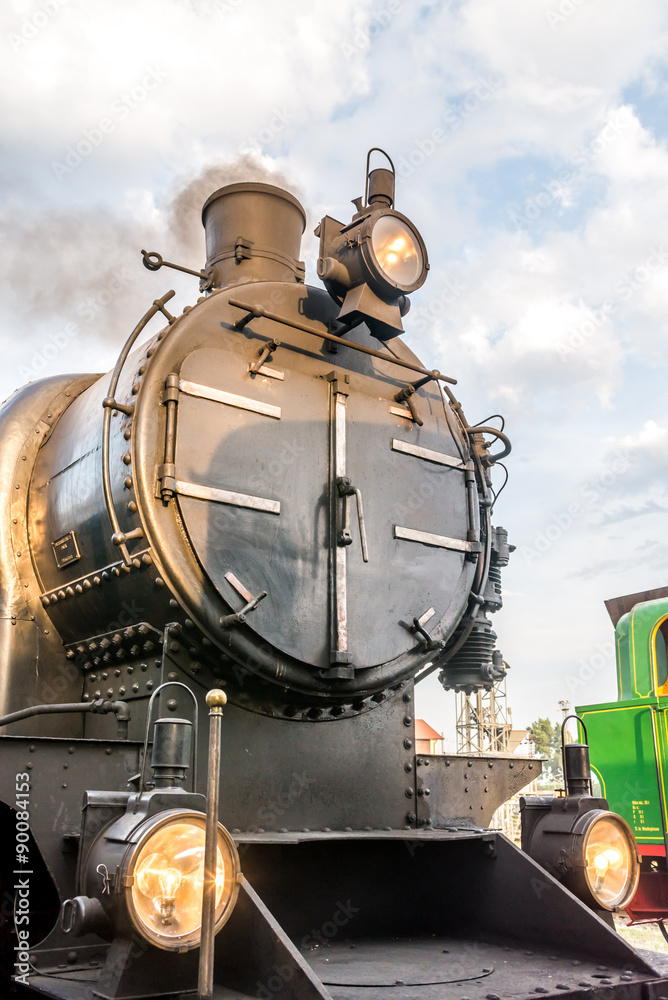 Old steam engine, front view with yellow lights, smoking Stock Photo ...