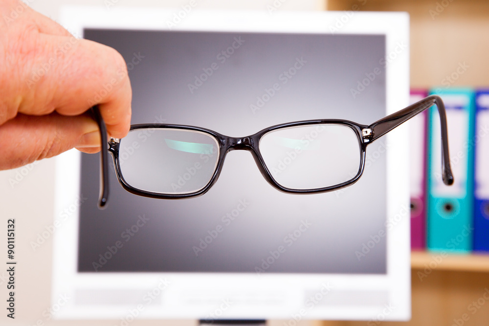 Hand holding glasses in front of computer screen Stock Photo | Adobe Stock