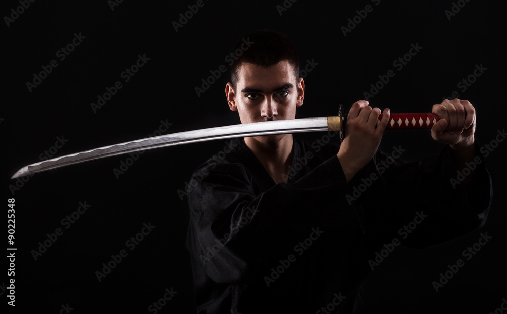Young martial arts fighter with katana on black background Stock Photo ...