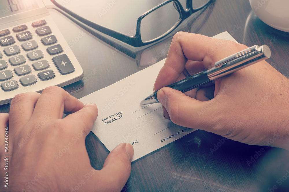 Man writing a payment cheque Stock Photo | Adobe Stock