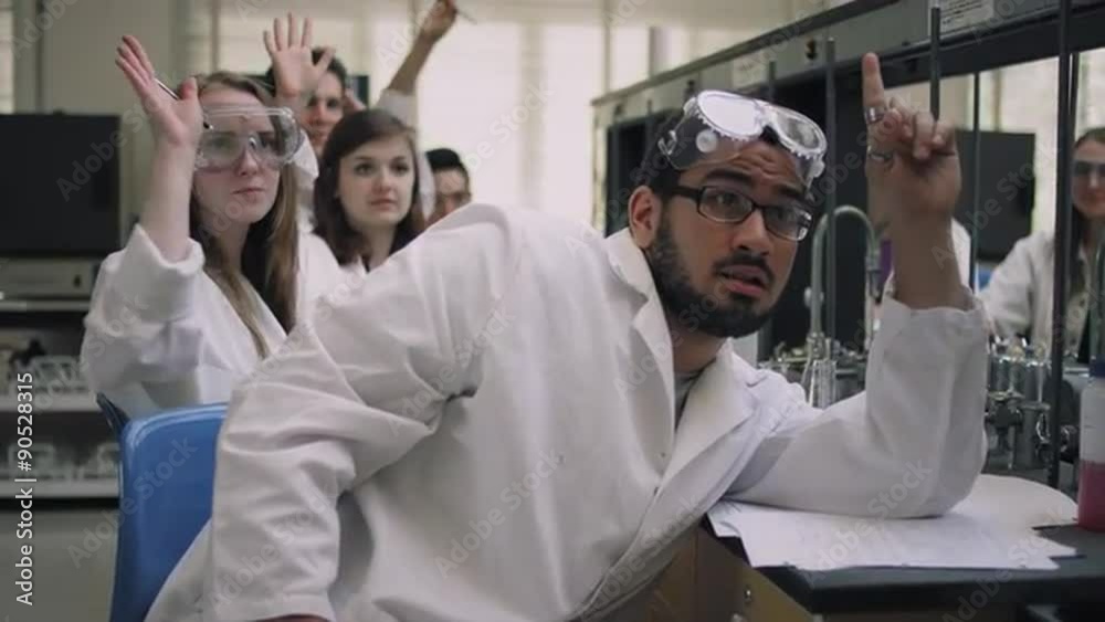 Students in a science lab listen to their professor and raise their ...