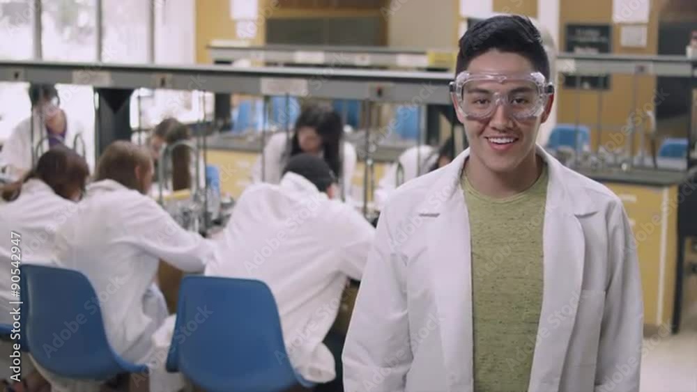 Portrait of a student in a science lab putting on safety goggles and ...