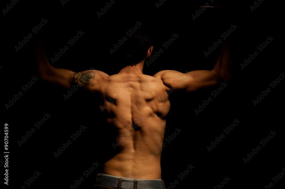 The back of the man showing his muscles on the black background Stock ...