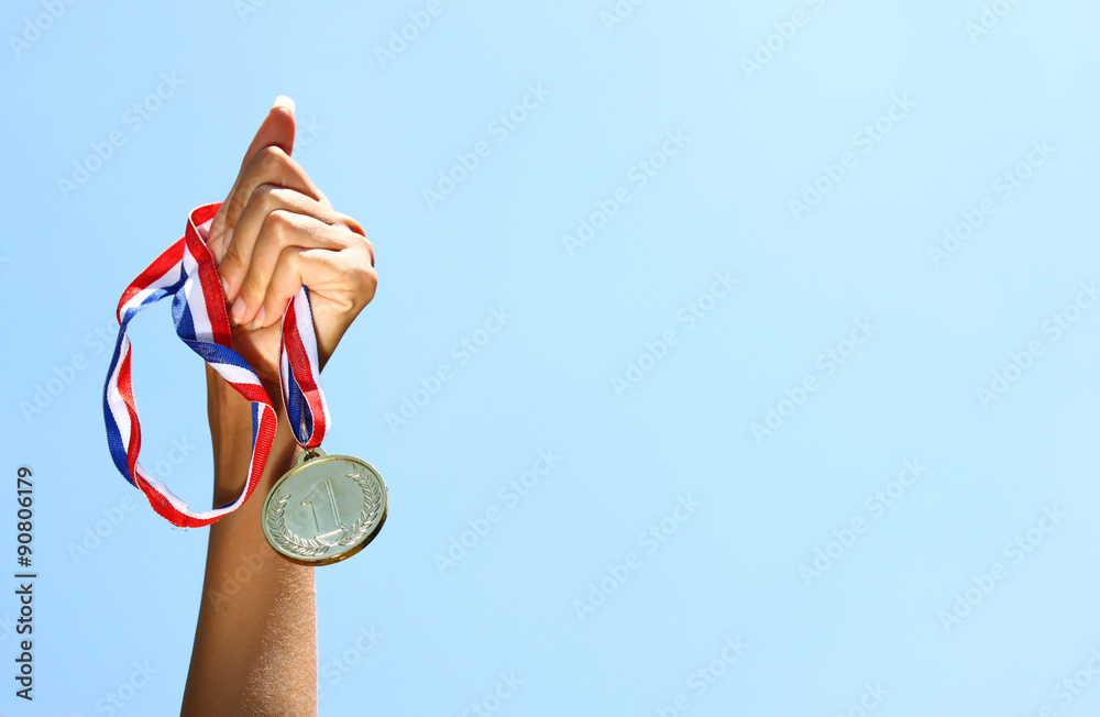 woman hand raised, holding gold medal against skyl. award and victory ...