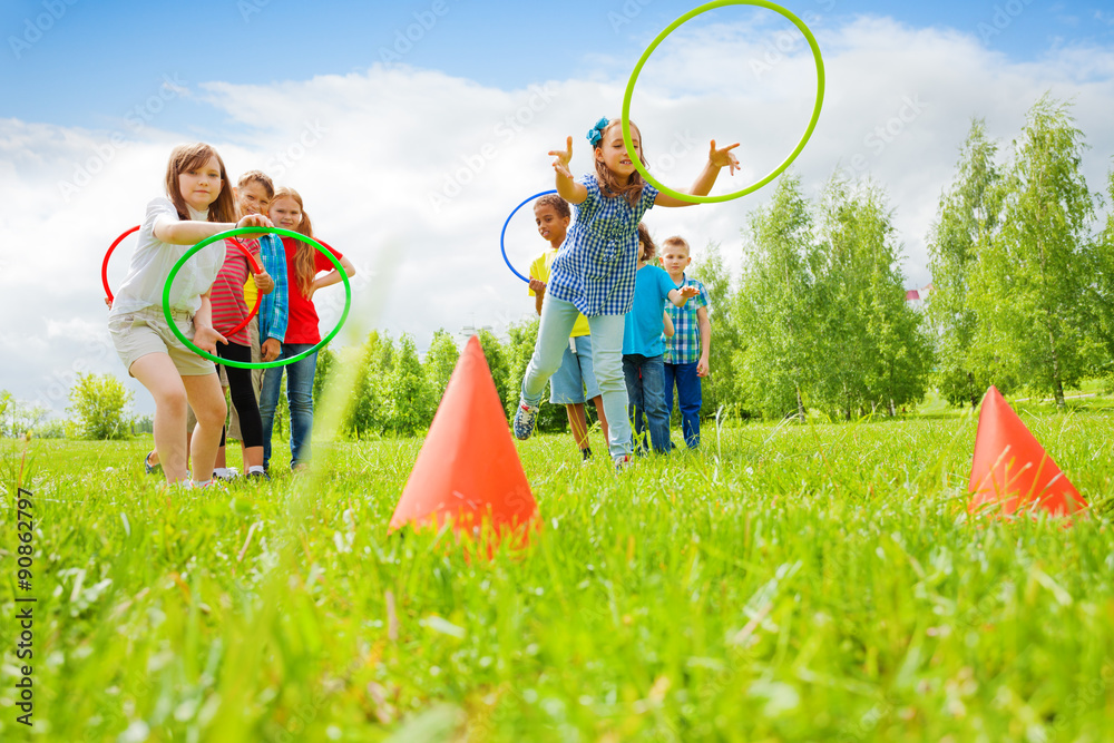 Kids playing and throwing colorful hoops on cones Stock Photo | Adobe Stock