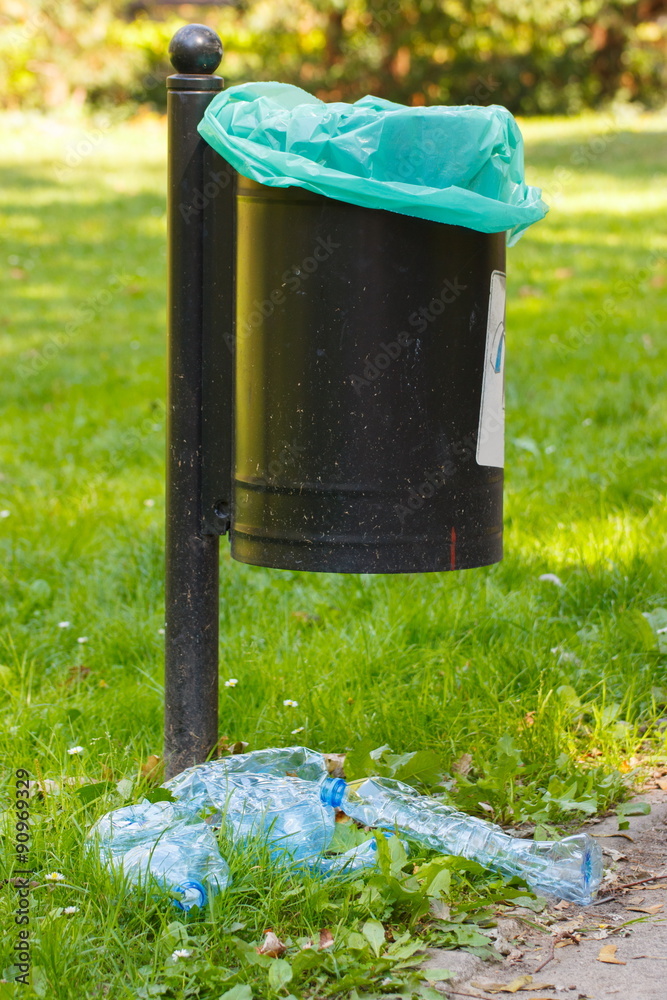 Trash can in park and heap of plastic bottles, littering of ...