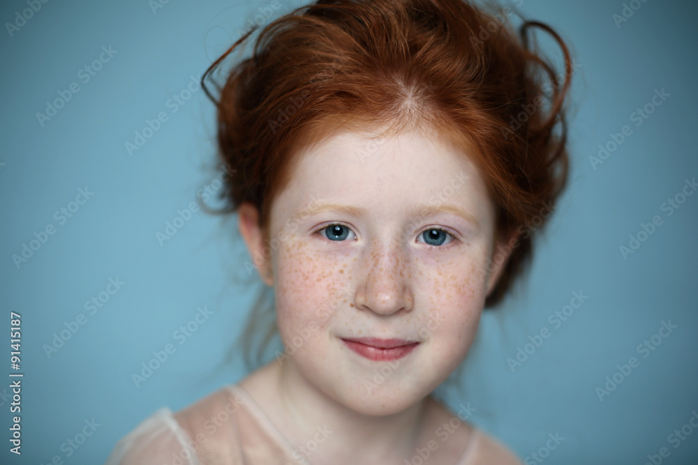 Portrait of beautiful redhead little girl. Blue background. Studio shot ...