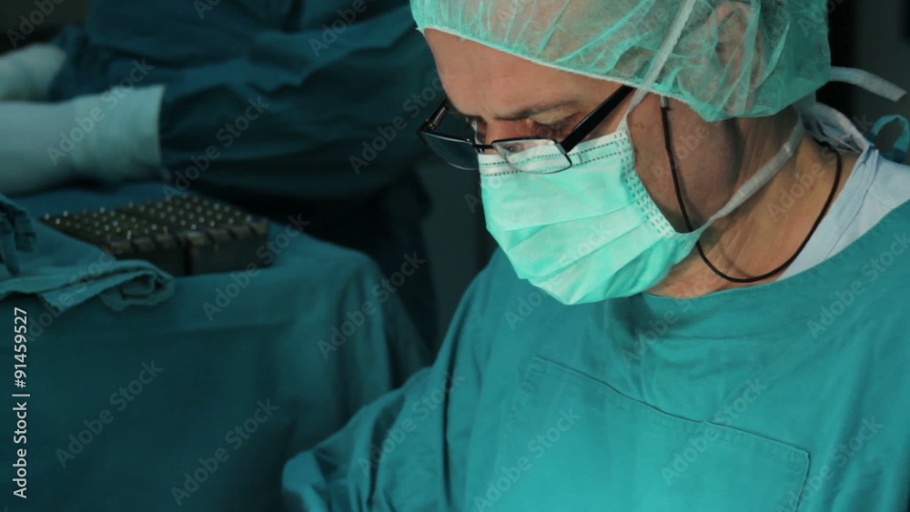 Surgeon face close up,performing surgical operation,tilt down to ...