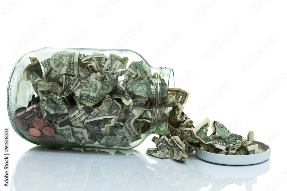 Glass jar full of money tipped over on its side spilling money w Stock ...