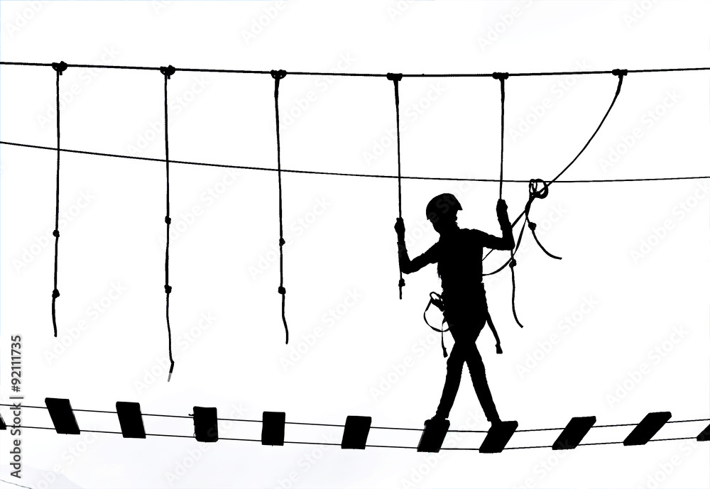 girl overcomes obstacles in the rope park. black silhouette of the girl ...