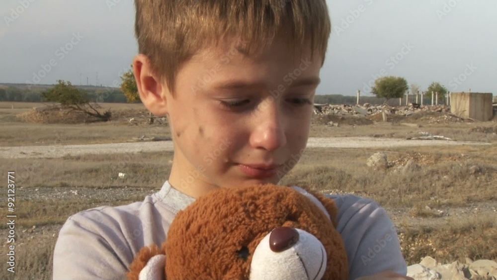 dirty little orphan boy close-up crying and petting a stuffed Stock ...