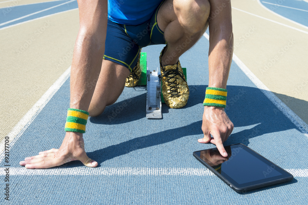 Athlete crouching at the starting blocks of a running track wearing ...