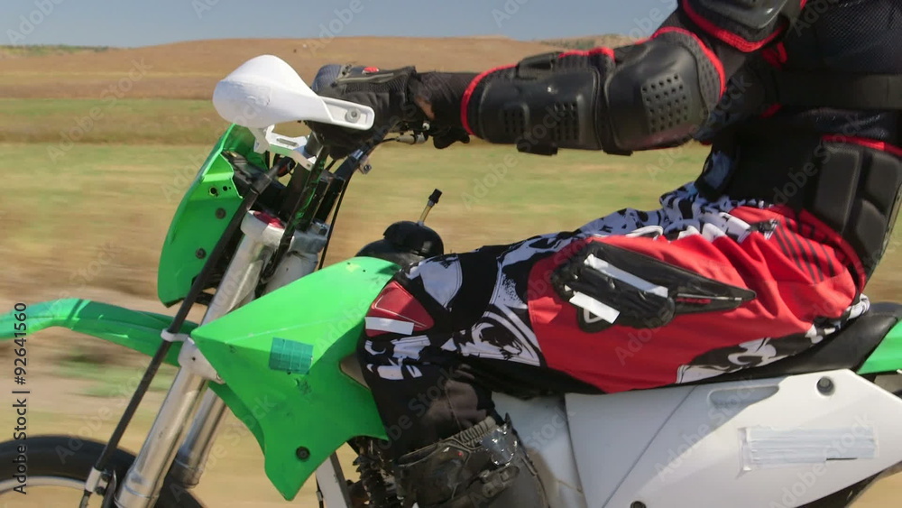 Motocross racer riding dirt bike, vehicle shot side view closeup tilt ...