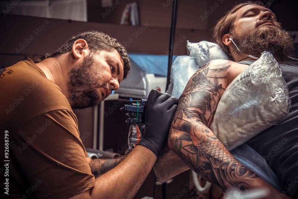 Professional tattooer showing process of making a tattoo in tattoo ...