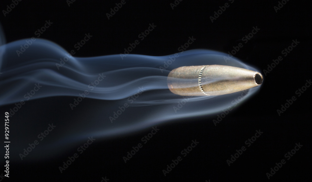 Speeding bullet with smoke behind after a shooting on a black ...