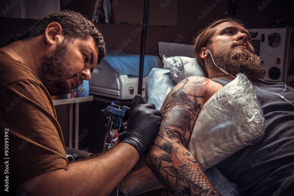 Professional tattooer showing process of making a tattoo in tatoo salon ...