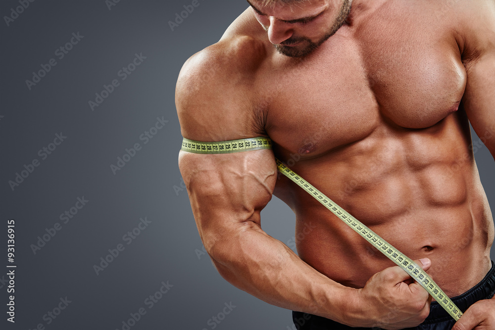 Closeup Muscular bodybuilder measuring biceps with tape measure ...