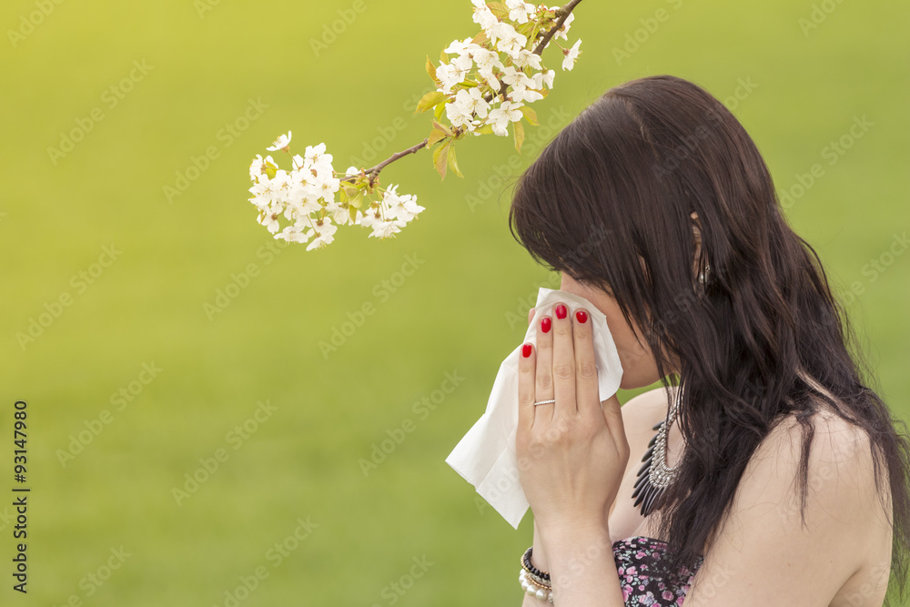 Beautiful hayfever girl wiping her nose in spring nature. The beautiful ...