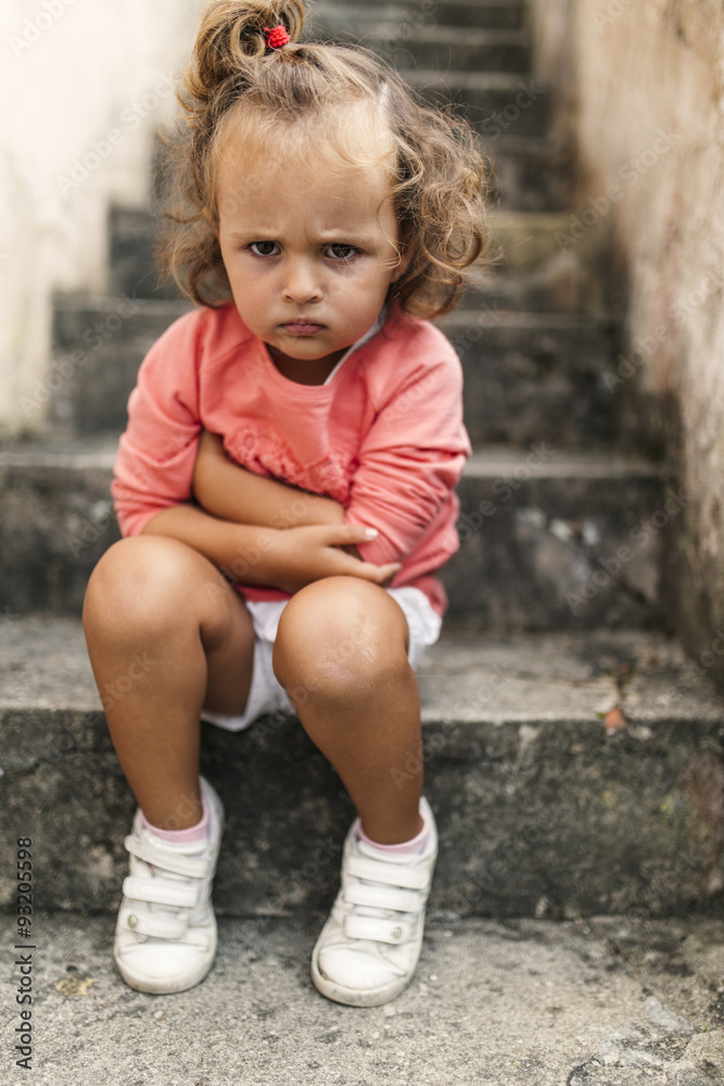Portrait of little girl sitting on steps pouting mouth Stock Photo ...