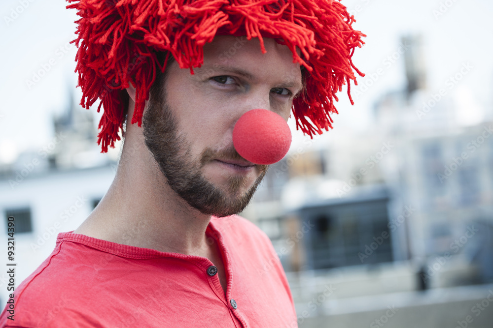 Germany, Cologne, portrait of bearded young man wearing clown's nose ...