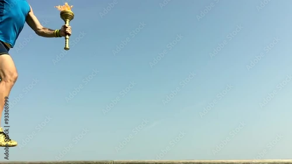 Torchbearer athlete in blue running with sport torch in slow motion ...