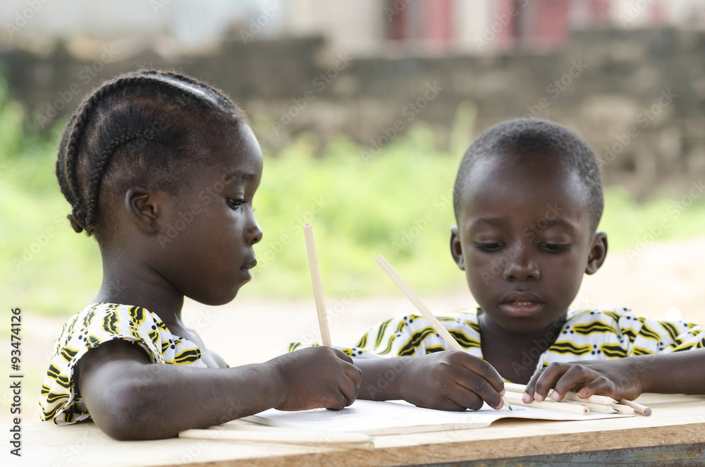 Black African ethnicity boy and girl sitting outdoors writing and ...