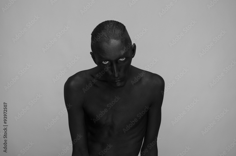 Gothic and Halloween theme: a man with black skin is isolated on a gray ...