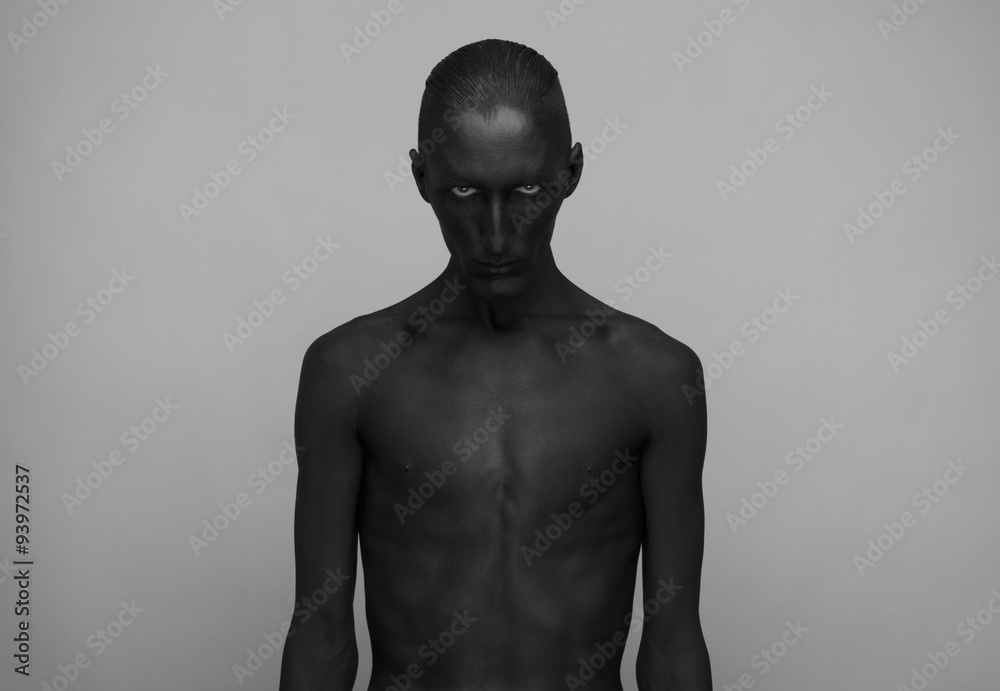 Gothic and Halloween theme: a man with black skin is isolated on a gray ...