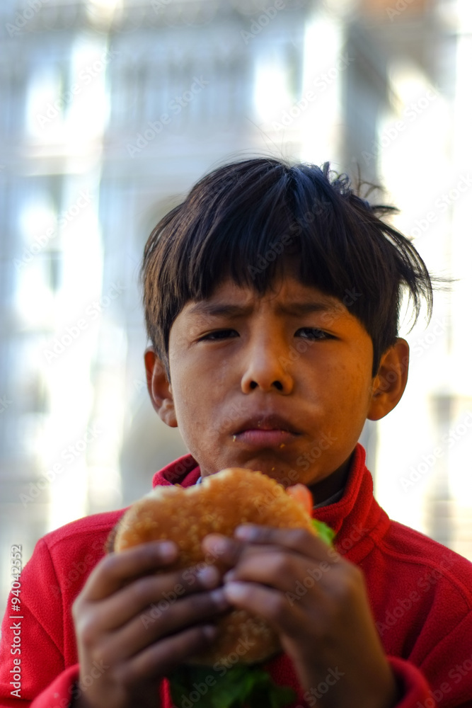 Male young child eating hamburger in from of Florence Duomo, Italy ...