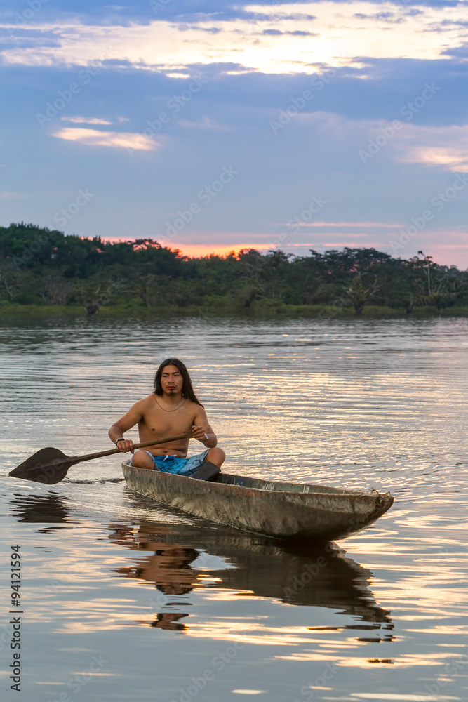 An indigenous Indian family paddles a wooden canoe on the Amazon River ...